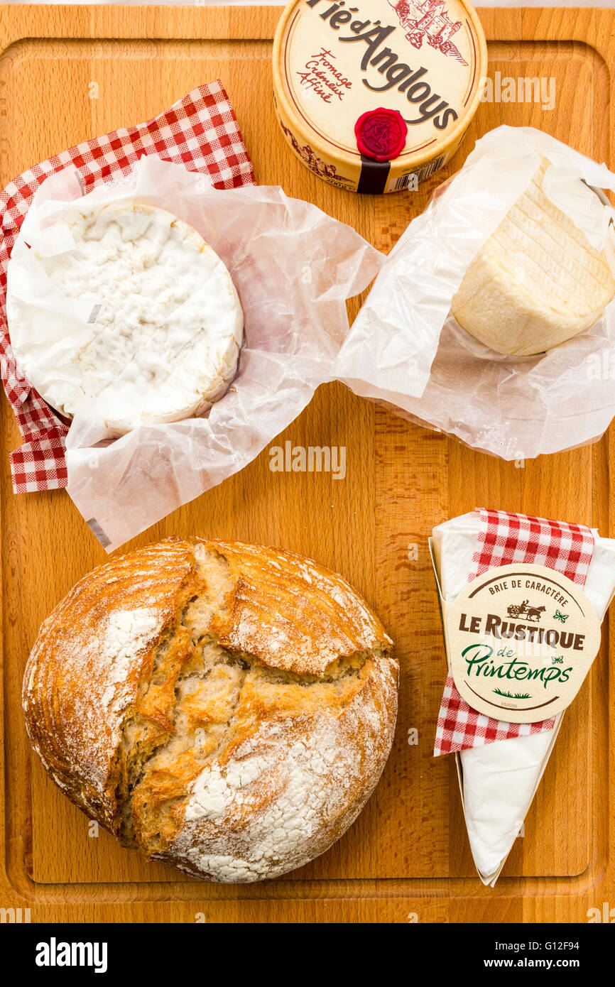 French Cheeses, boxed and some opened, on wooden chopping board with ...