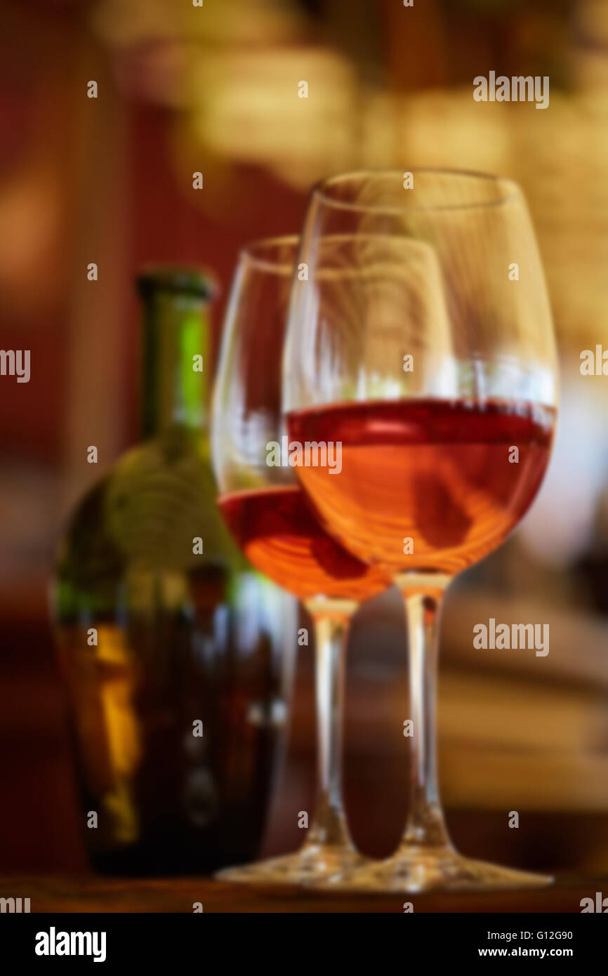 two wine glasses filled with red wine and wine bottle in background ...