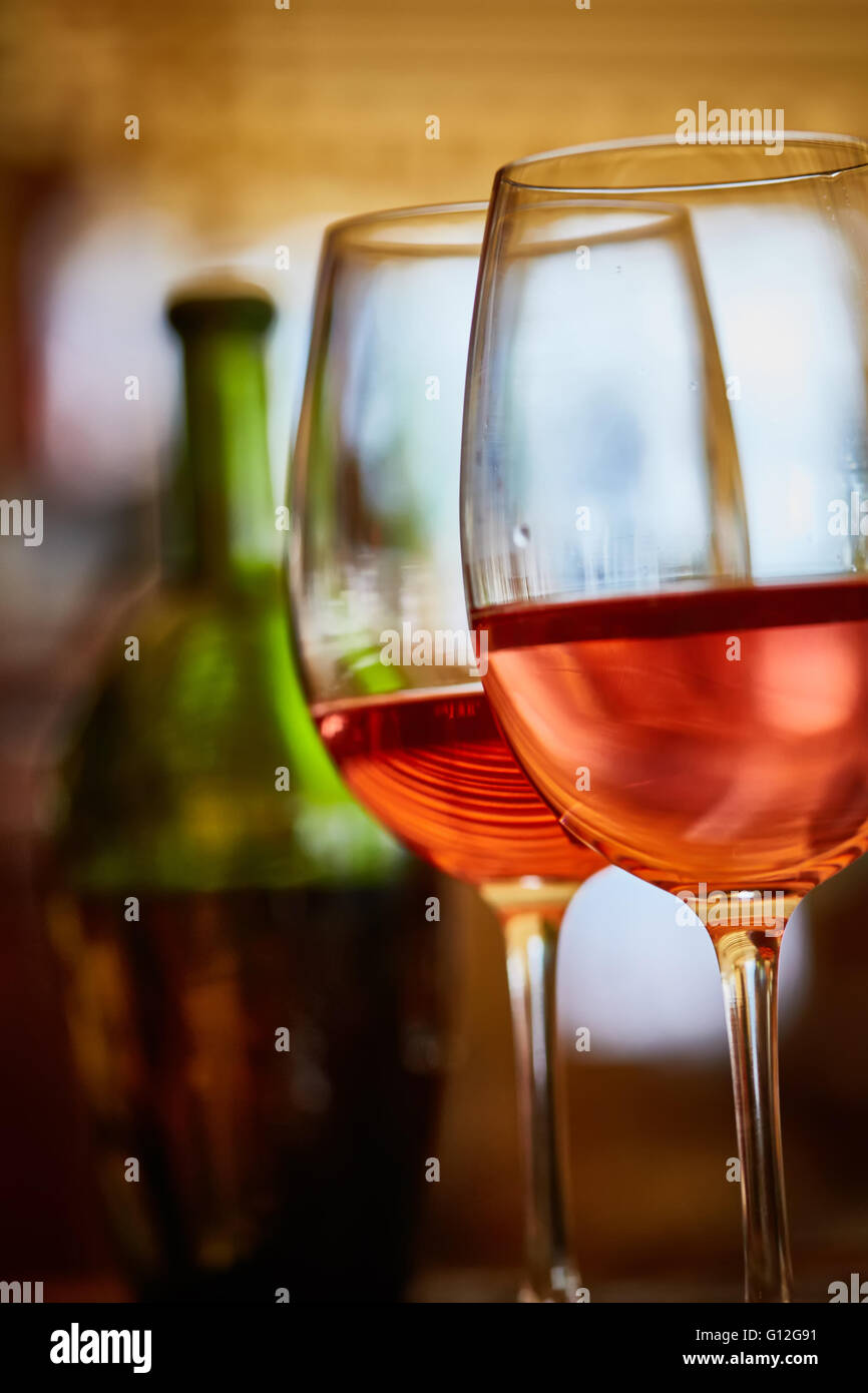 two wine glasses filled with red wine and wine bottle in background ...