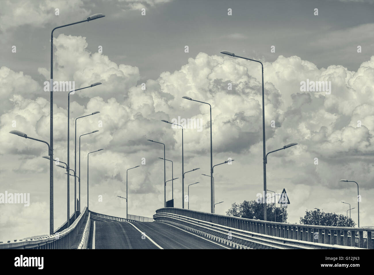 Empty interstate road with highway lamp posts over cumulus clouds in ...