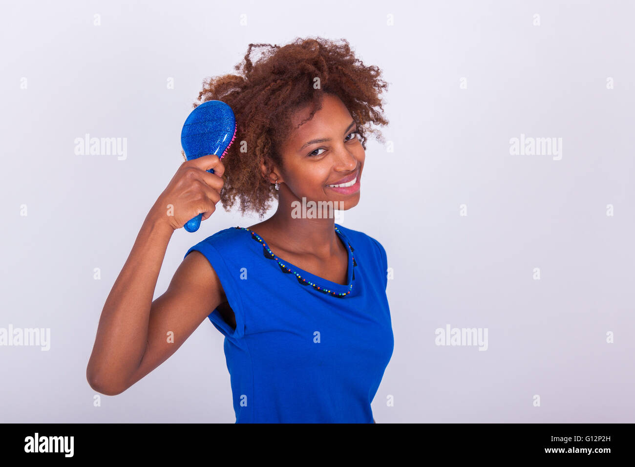 Young African American woman combing her frizzy afro hair - Black ...