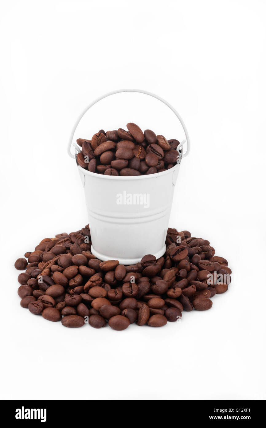 White bucket full of coffee beans, stands on a heap coffee beans, on a ...