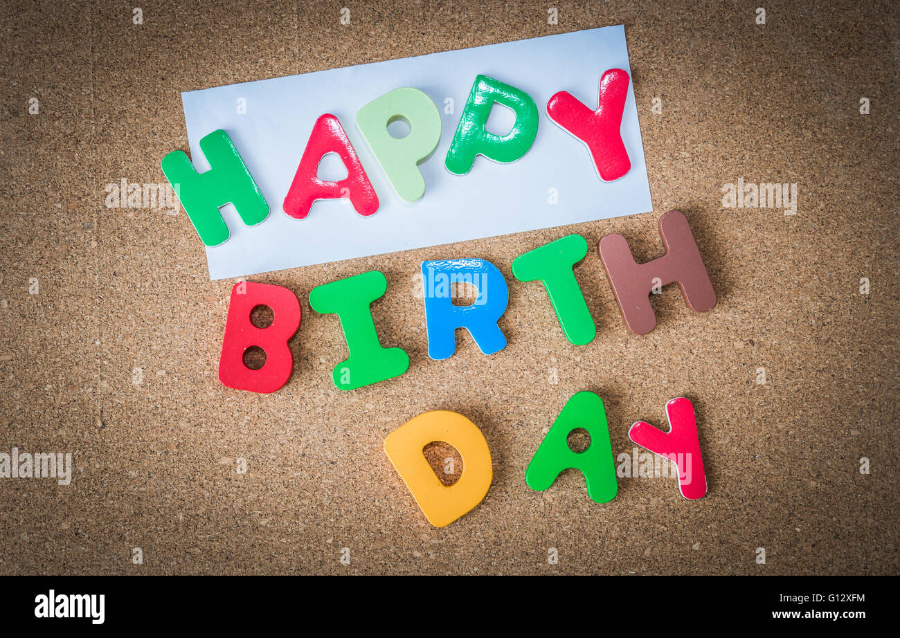 Colorful Wooden word HAPPY BIRTH DAY with piece of White paper on cork ...