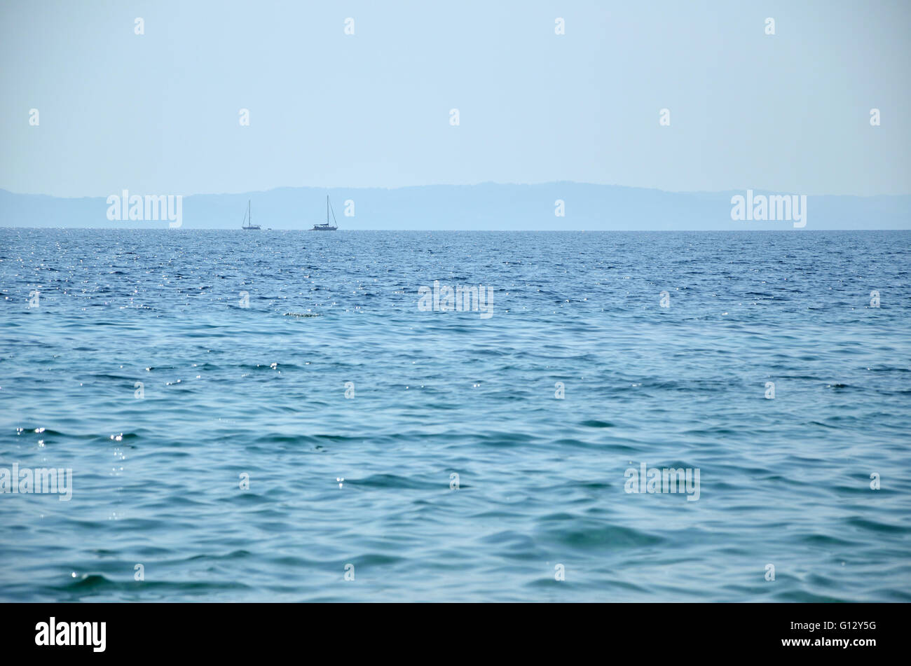 Two boats are sailing across the sea in distance Stock Photo - Alamy