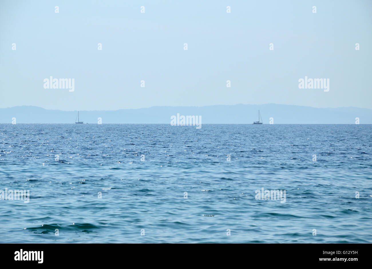 Two boats are sailing across the sea in distance Stock Photo - Alamy