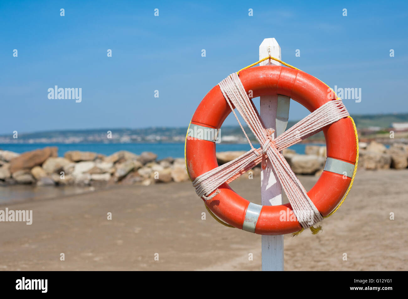 Red lifebuoy ready for safety use close up on empty beach background ...