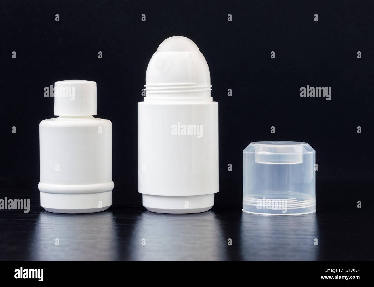 White roll on deodorant with cap off and a refill bottle on dark ...