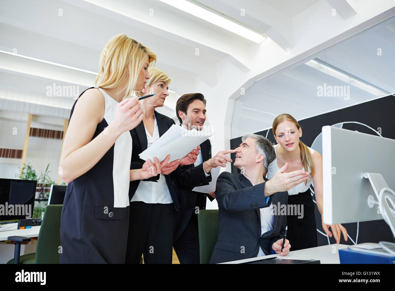 Business team in office looking at broken computer on desk Stock Photo ...