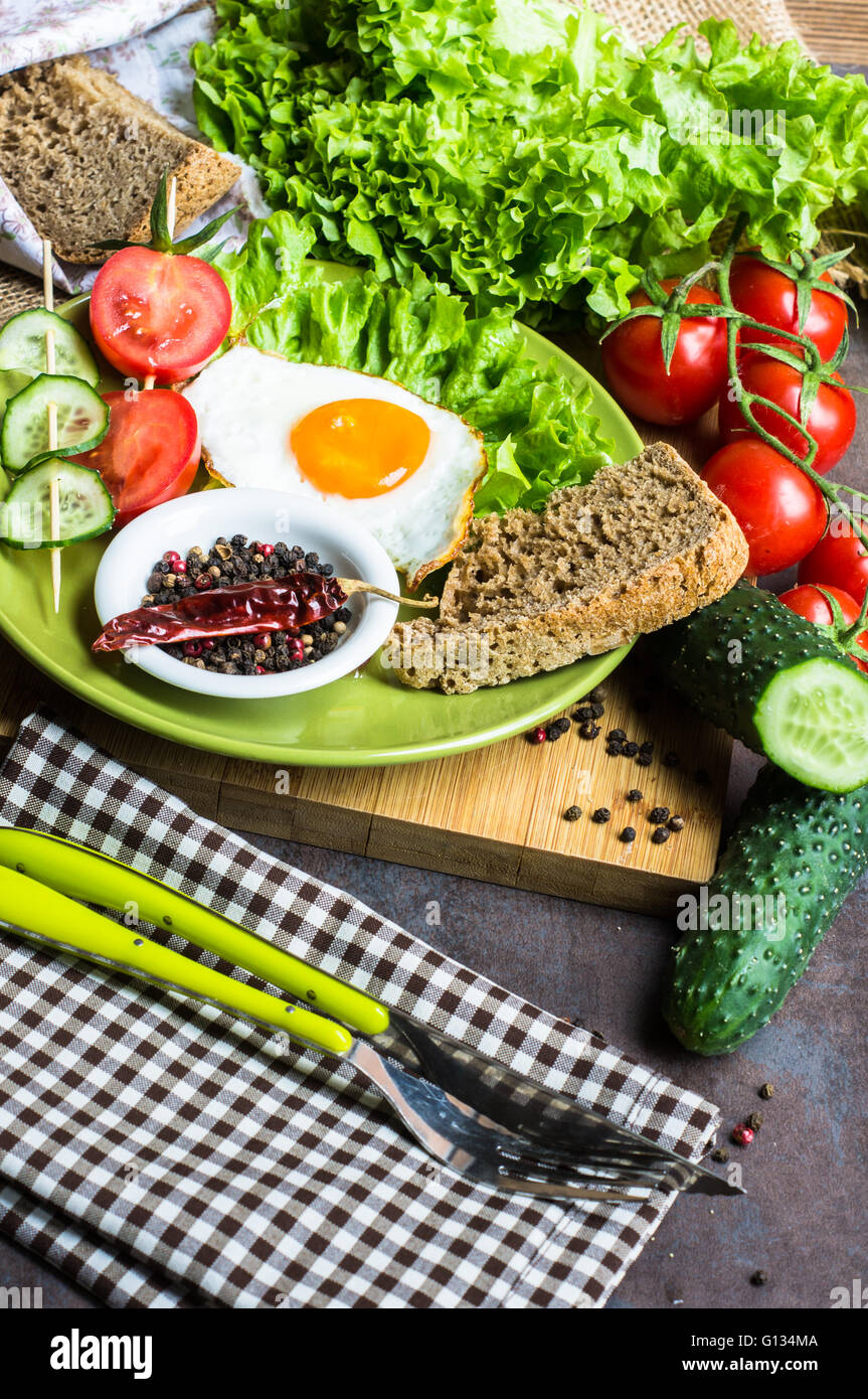 Breakfast with fried egg, cherry-tomatoes and spices on rustic kitchen ...