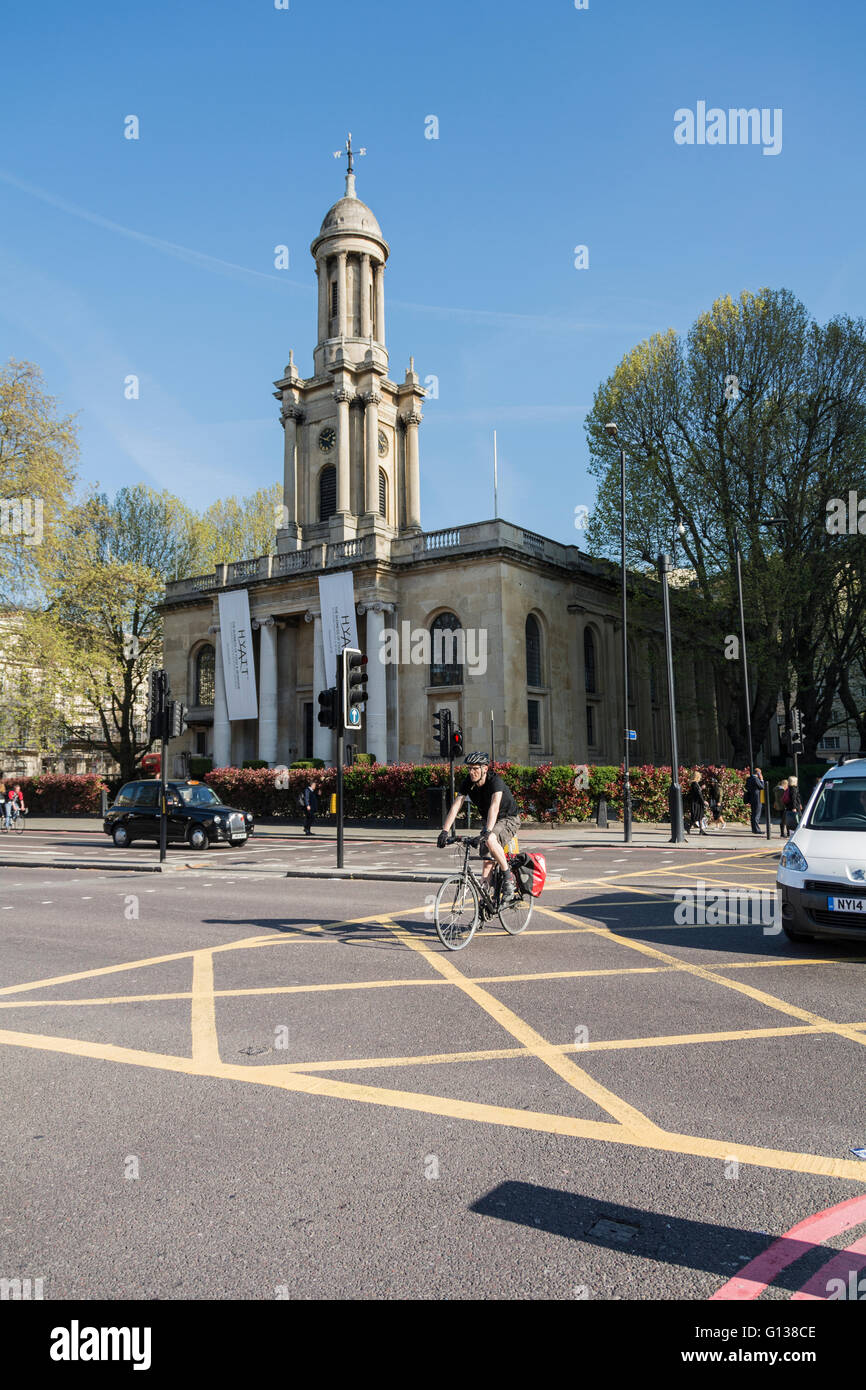 A cyclist passes the Holy Trinity church building on a busy Marylebone ...