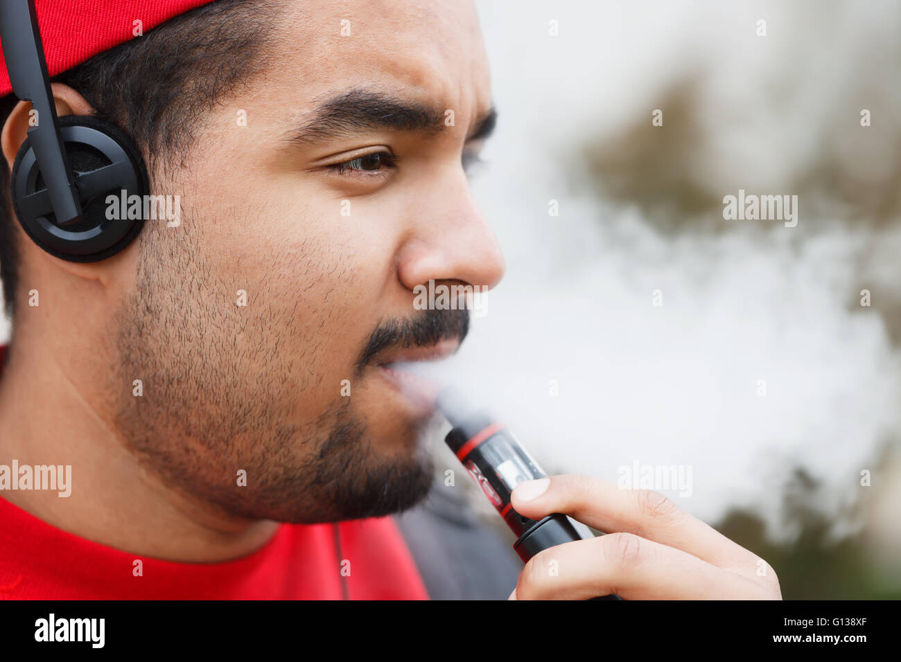 Portrait of black boy using modern e-cig vaporizer device for smoking ...