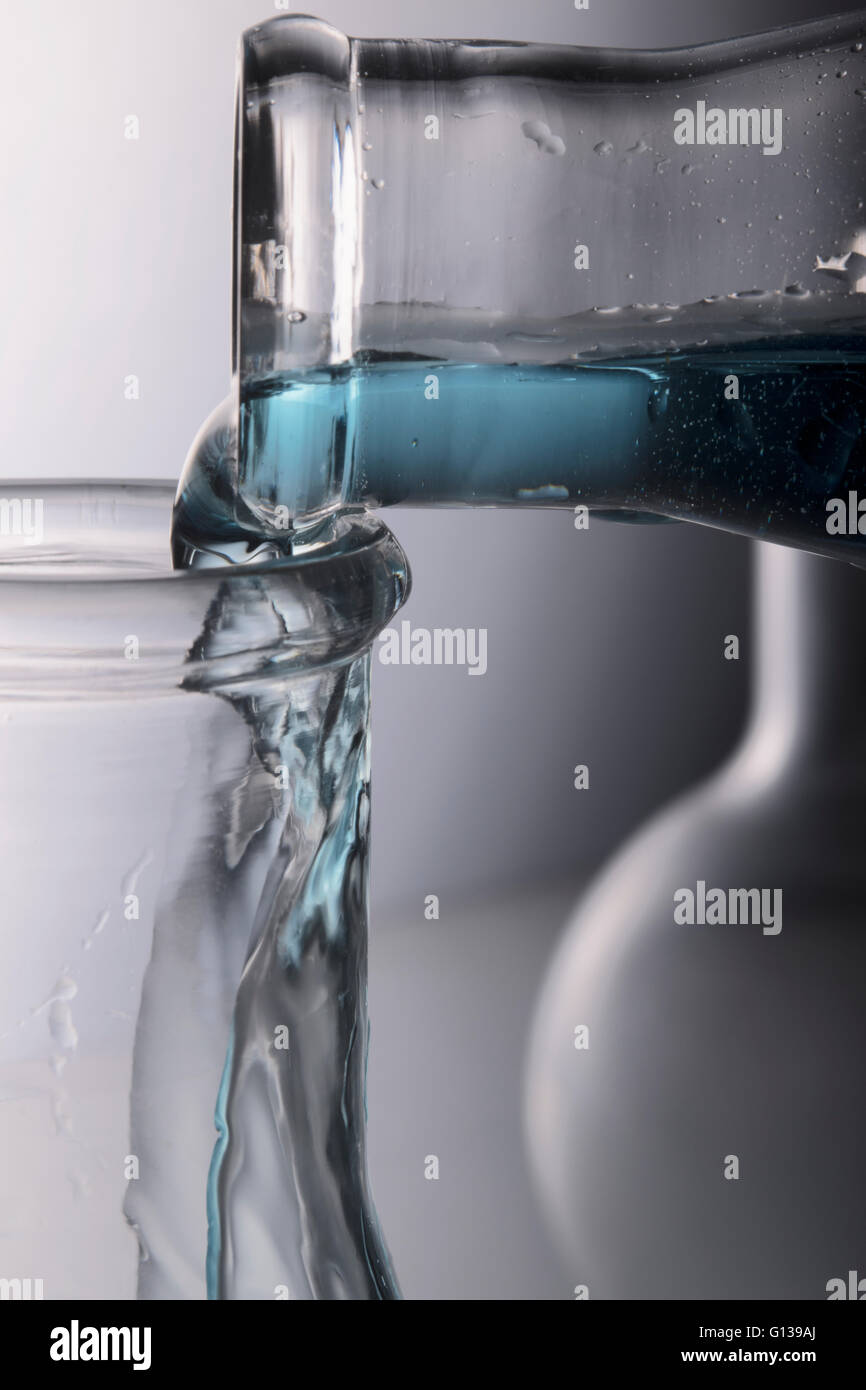 Blue chemistry being poured into Erlenmeyer flask, boiling flask in ...