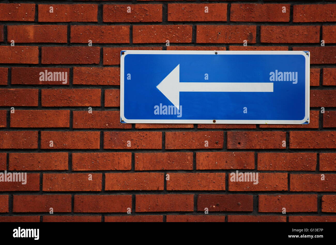Arrow sign on a red brick wall Stock Photo - Alamy