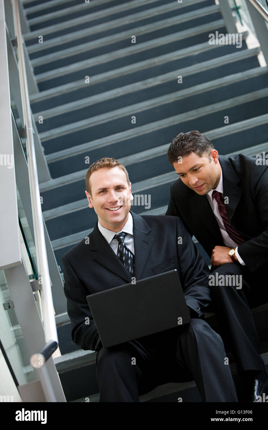 Businesspeople in various poses by glass staircase Stock Photo - Alamy