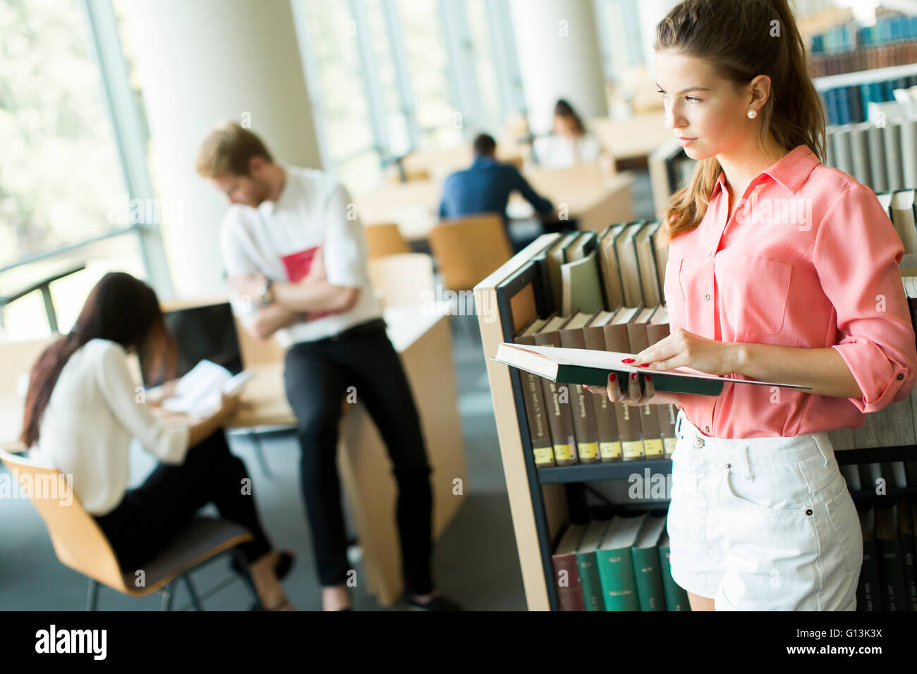 Woman reading a book in the library Stock Photo - Alamy