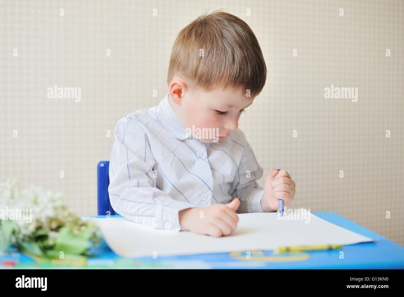 Portrait of cute boy with pen and paper at desk in classroom Stock ...
