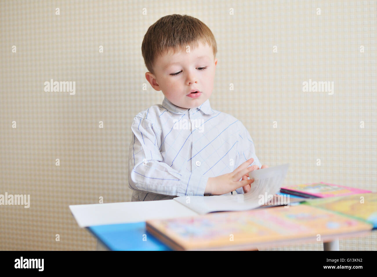 Portrait of cute boy with pen and paper at desk in classroom Stock ...