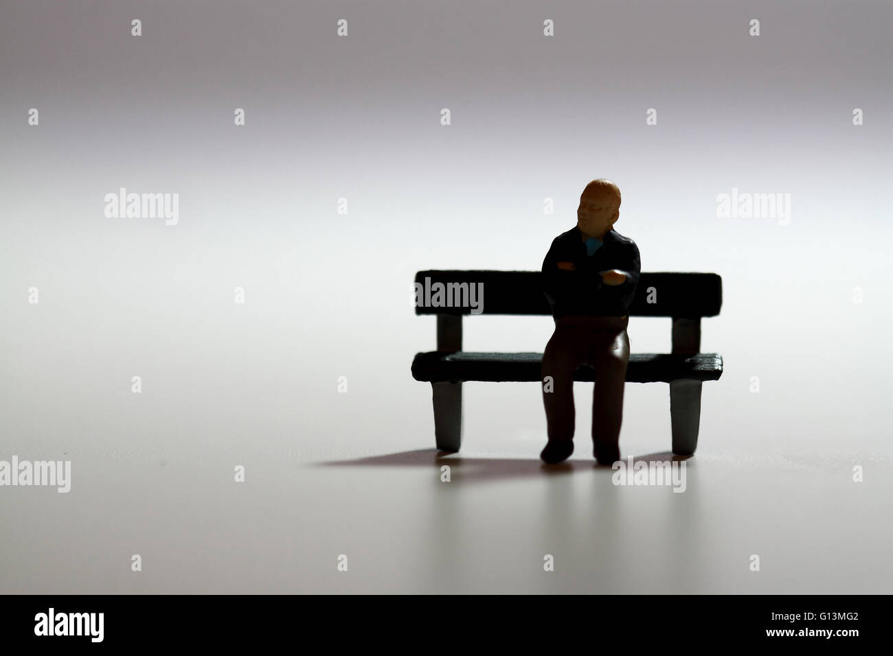 Miniature model of a senior man sitting on a bench Stock Photo - Alamy