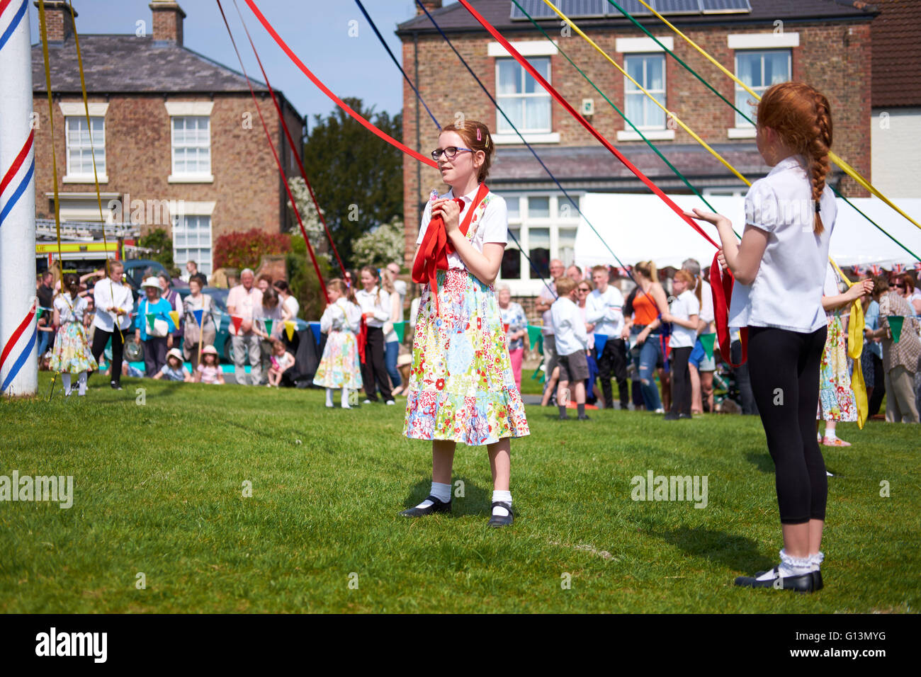 A young girl holds her ribbon during in a pause in the dancing around ...