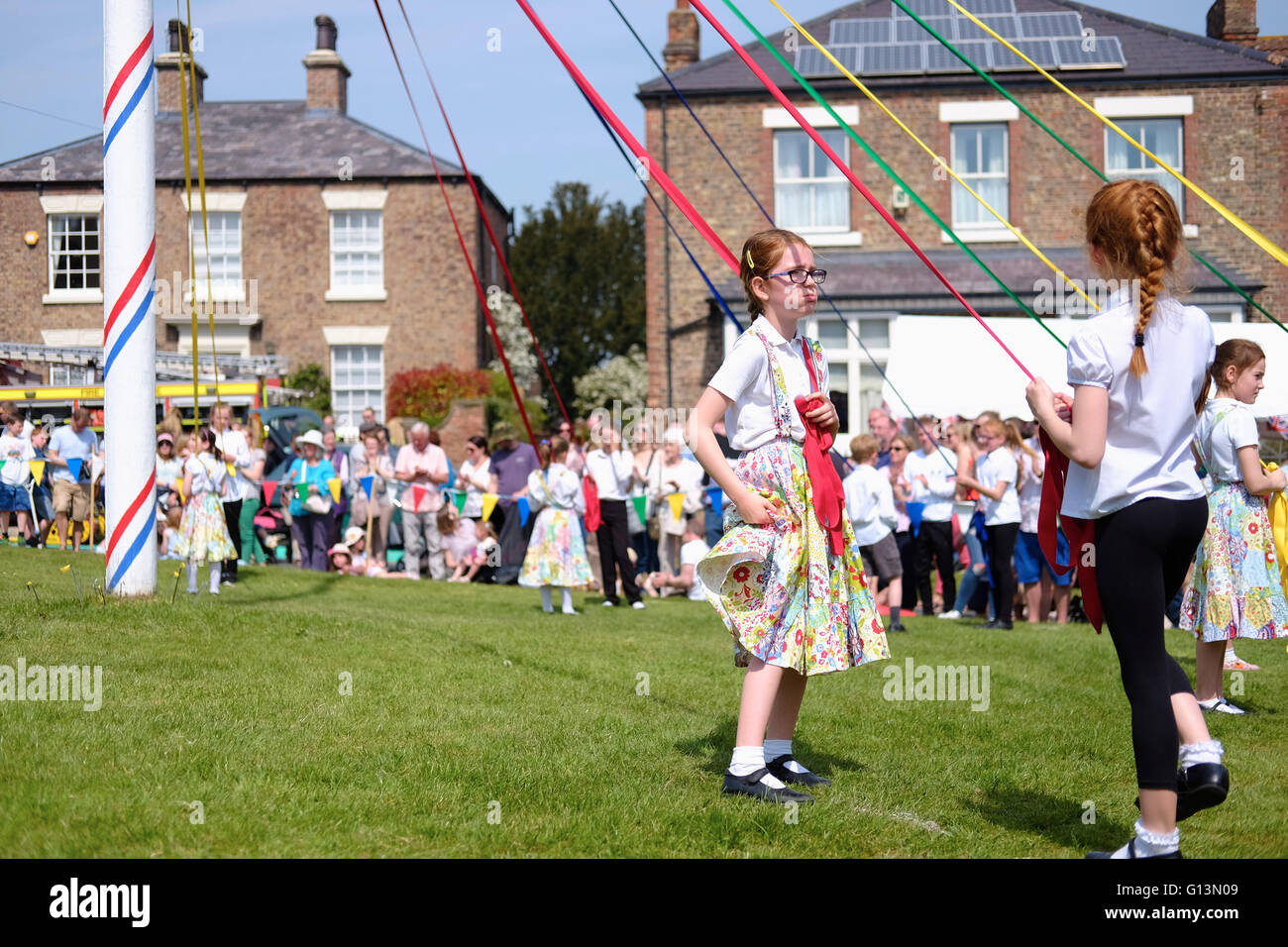 A young girl feels the heat whilst dancing around the maypole during ...