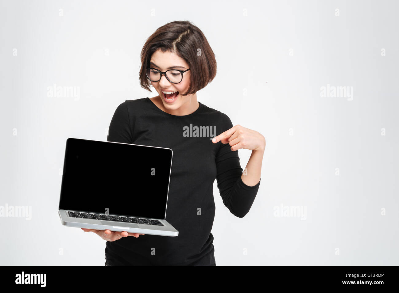 Cheerful woman pointing finger on blank laptop computer screen isolated ...