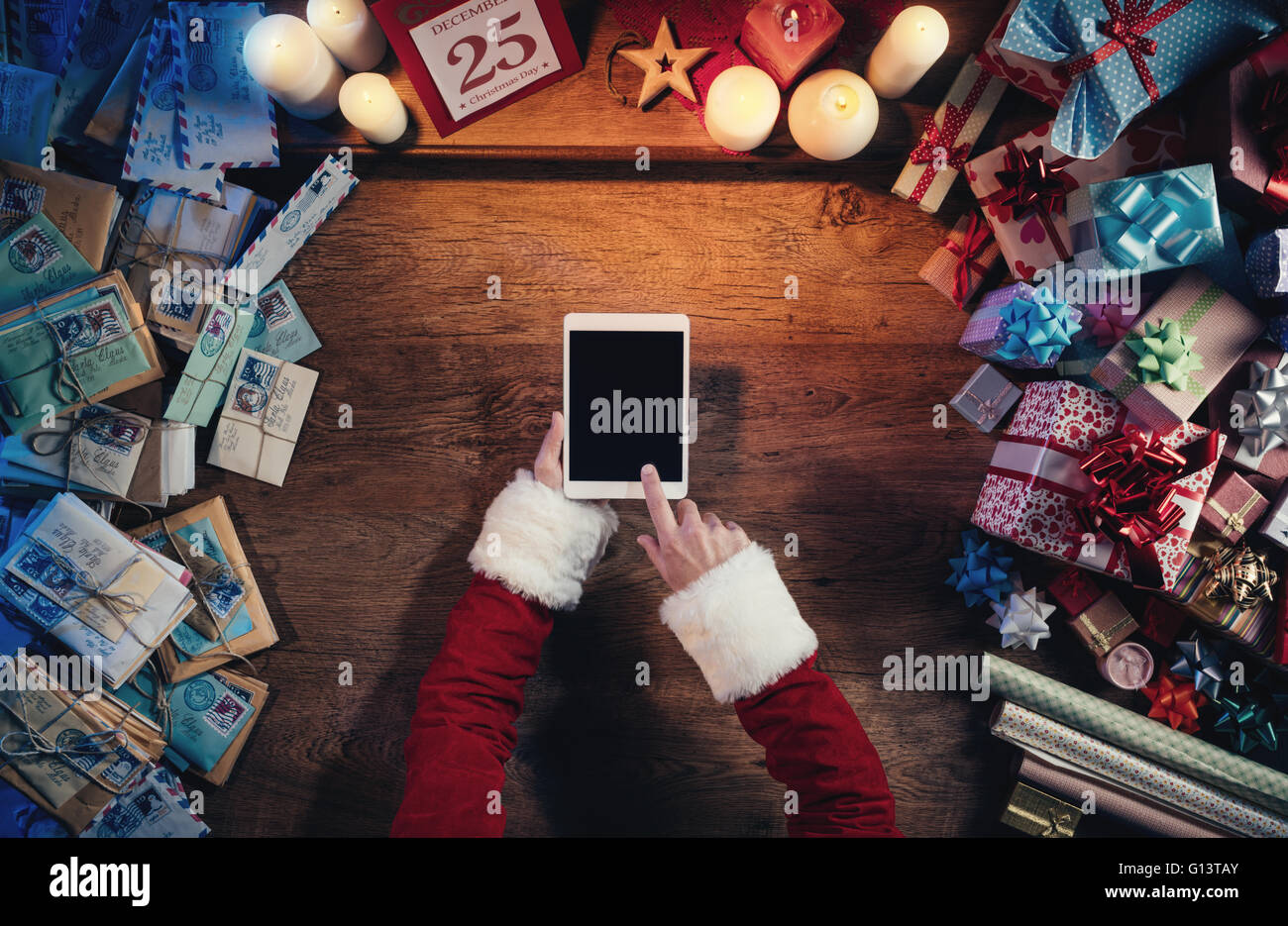 Santa Claus sitting at his desk and using a digital touch screen tablet ...