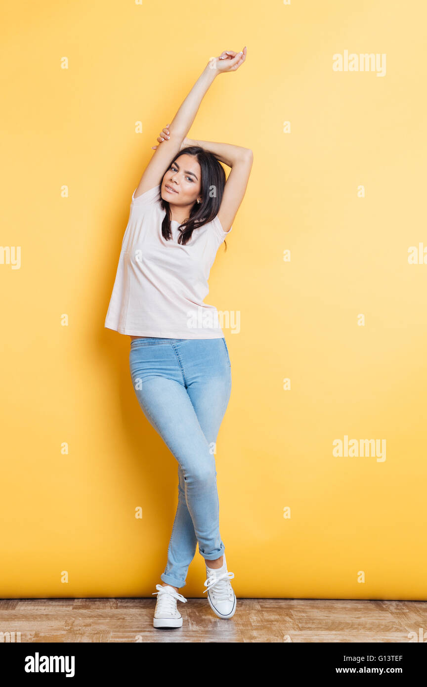 Full length portrait of a stylish woman posing on yellow background ...