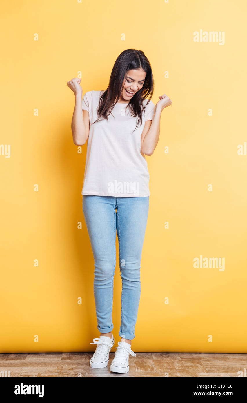 Full length portrait of a successful woman standing on yellow ...