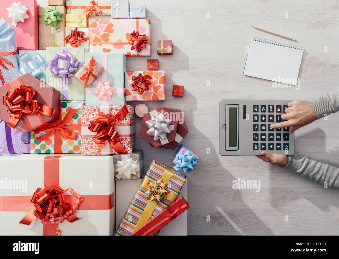 Man calculating costs with a calculator and lots of colorful gift boxes ...