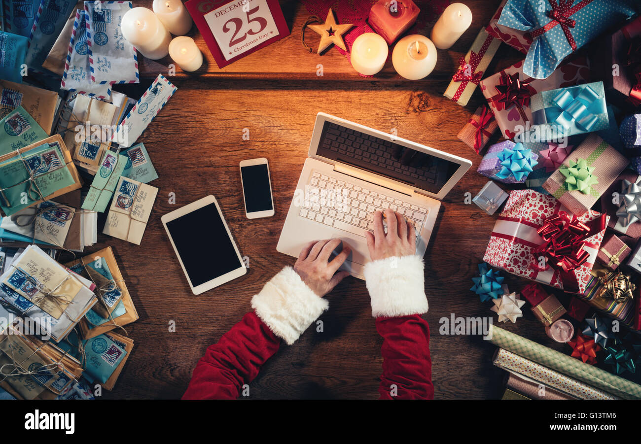 Hi-tech Santa Claus working at his desk and typing on a laptop ...