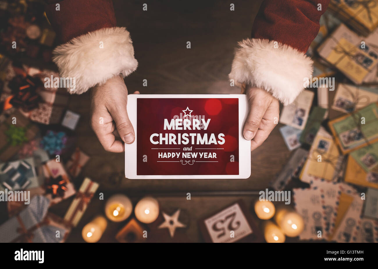 Santa Claus using a digital touch screen tablet with Merry Christmas ...