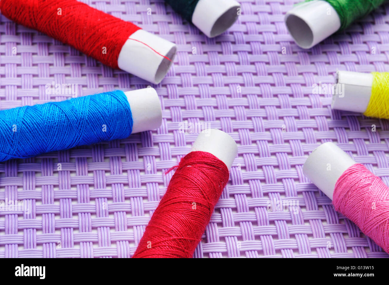 spools of sewing thread of different colors on a purple background ...