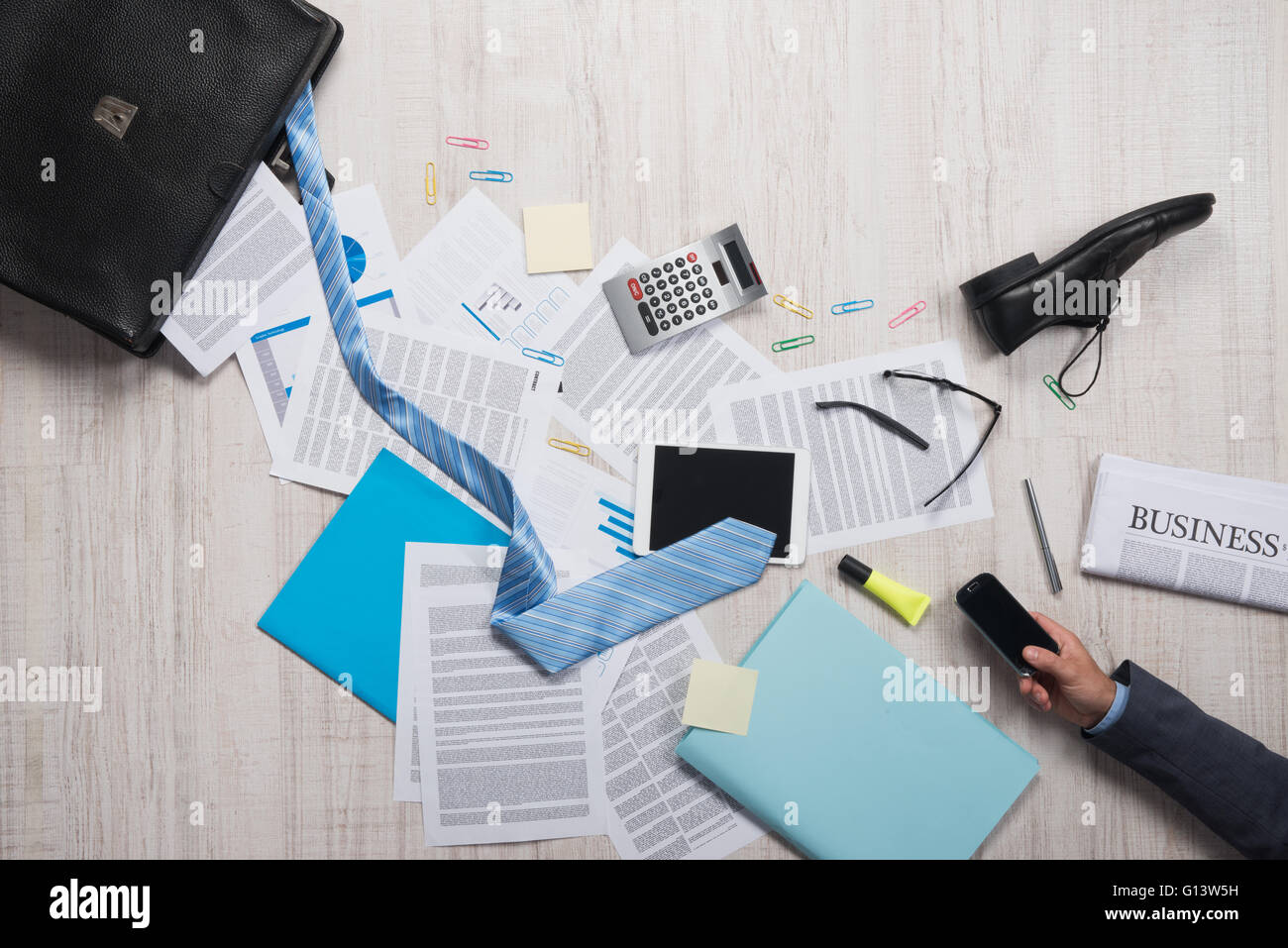 Businessman briefcase with paperwork and accessories on the floor ...