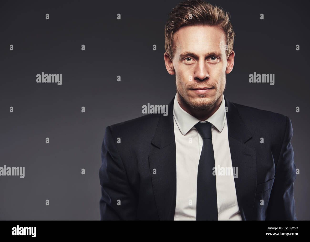 Blond handsome young man looking at camera with a serious and ...