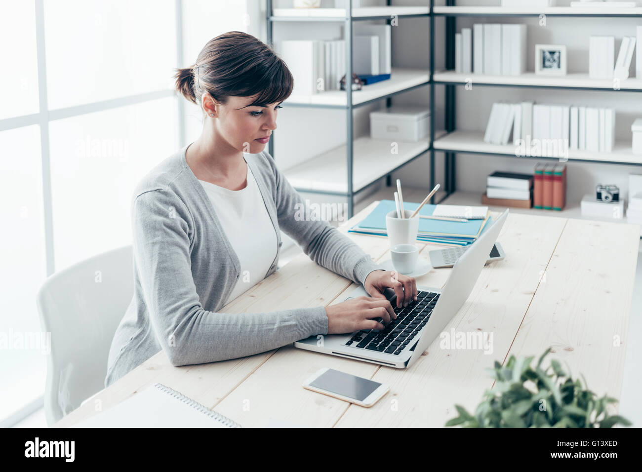 Confident young freelancer sitting at office desk and working with a ...