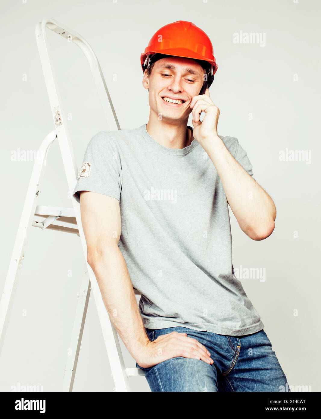 young real hard worker man isolated on white background on ladder ...