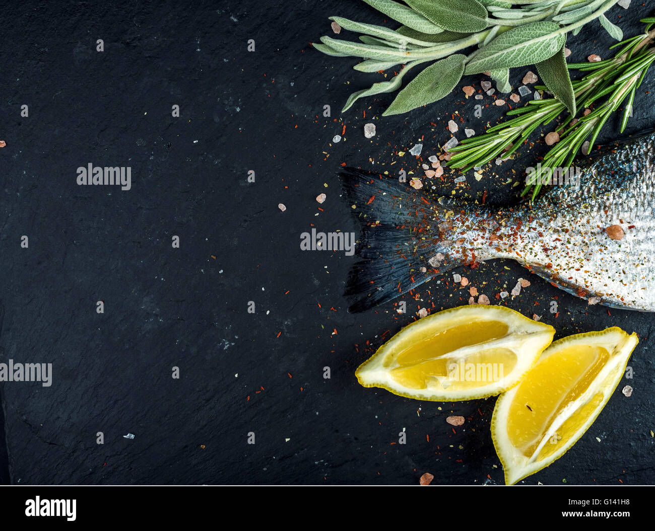 Tail of fresh raw Dorado or sea bream fish on black slate stone board ...