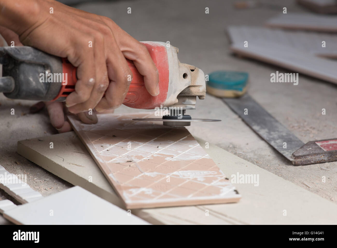 worker grinding a tile using an angle grinder at construction site ...