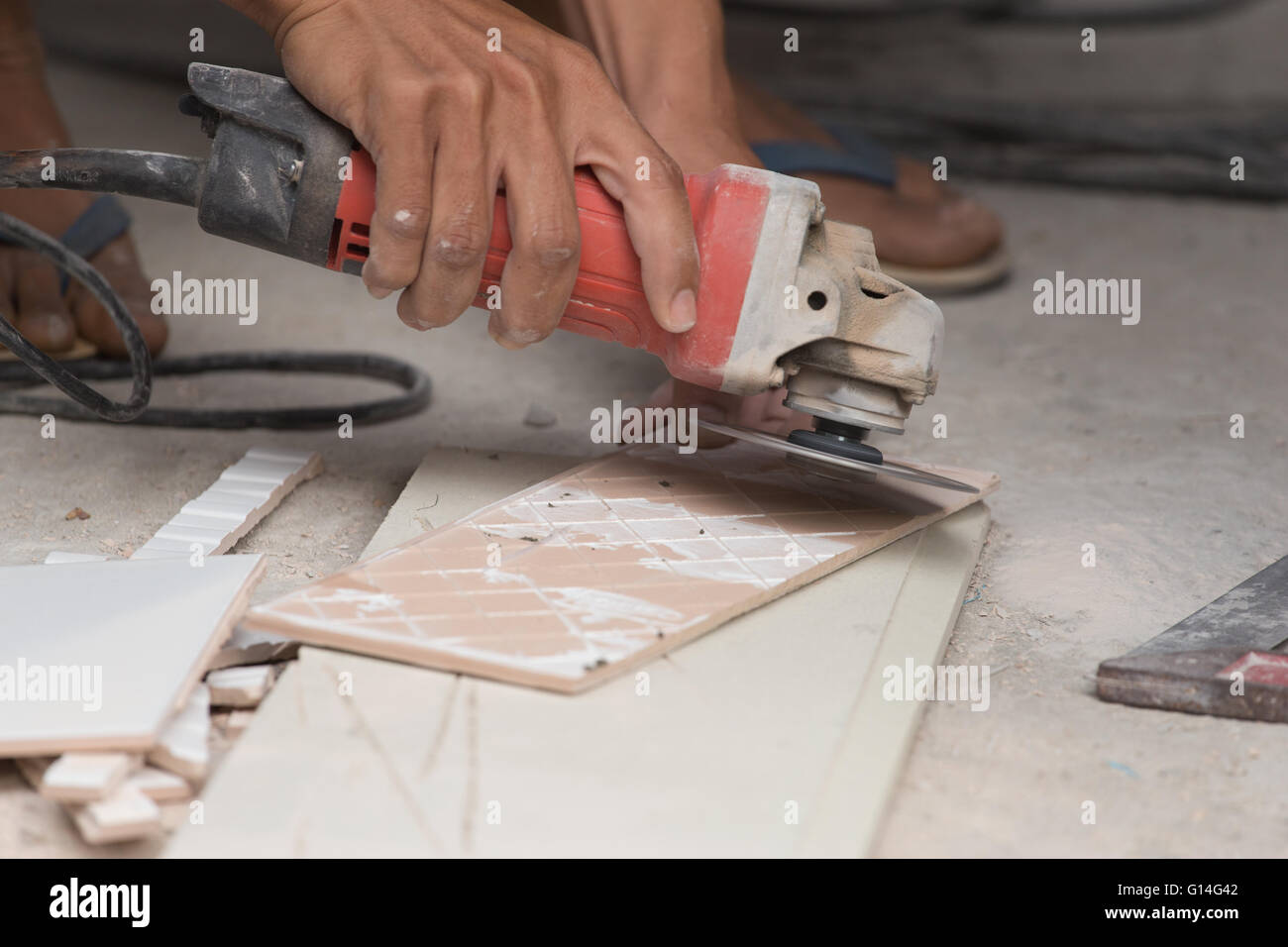 worker grinding a tile using an angle grinder at construction site ...
