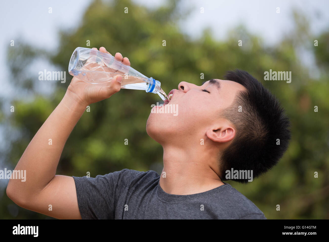 young man or teenager drinking water from plastic bottle Stock Photo ...