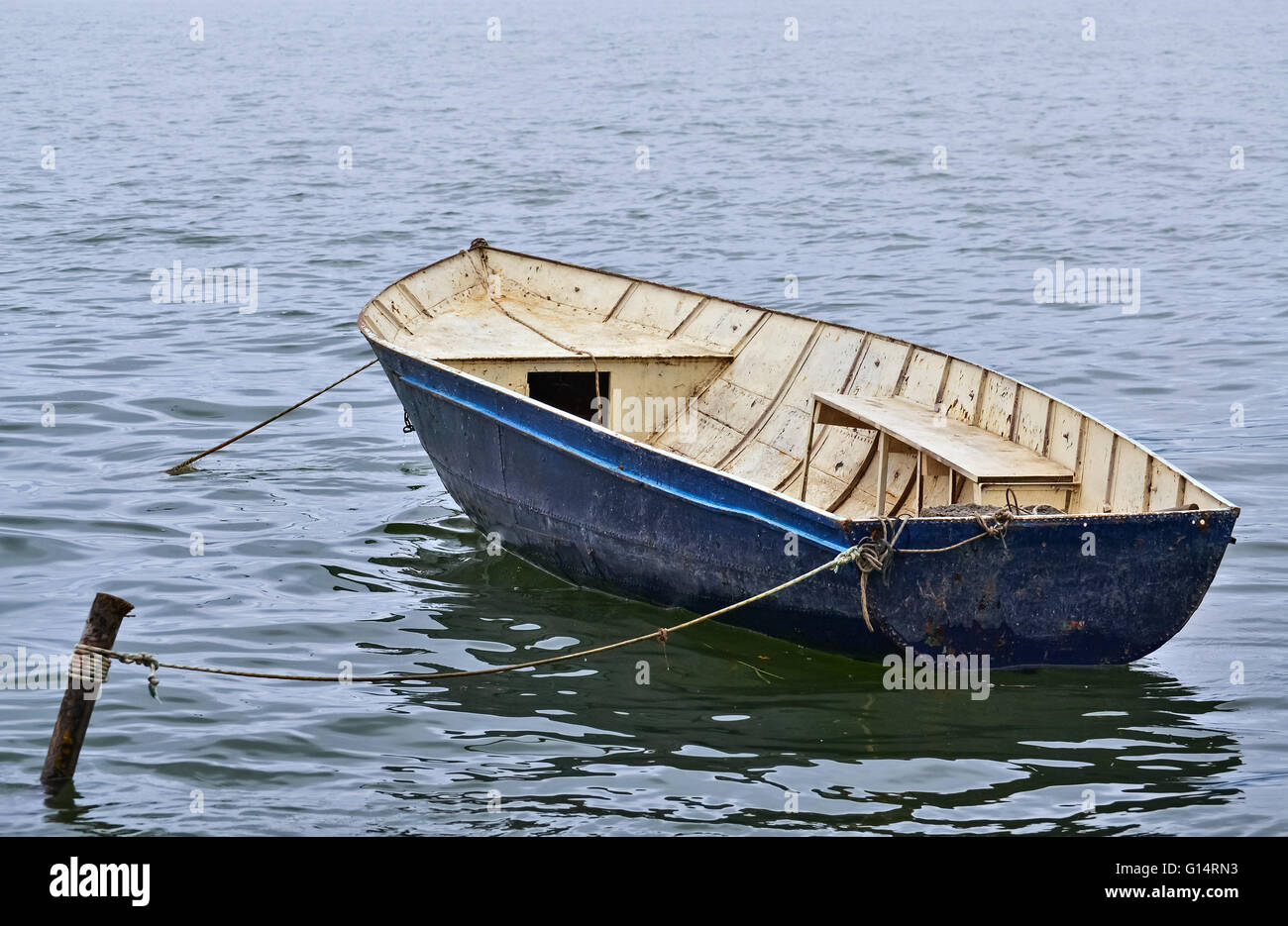 Small floating boat anchored on the shore of the lake Stock Photo - Alamy