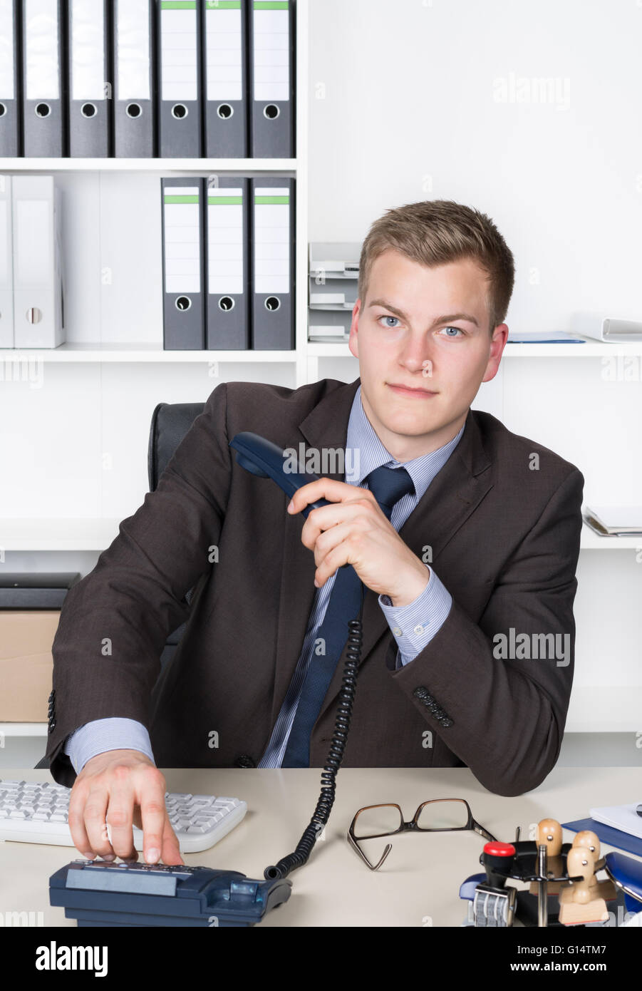 Young businessman is dialing a number at the phone while sitting at the ...