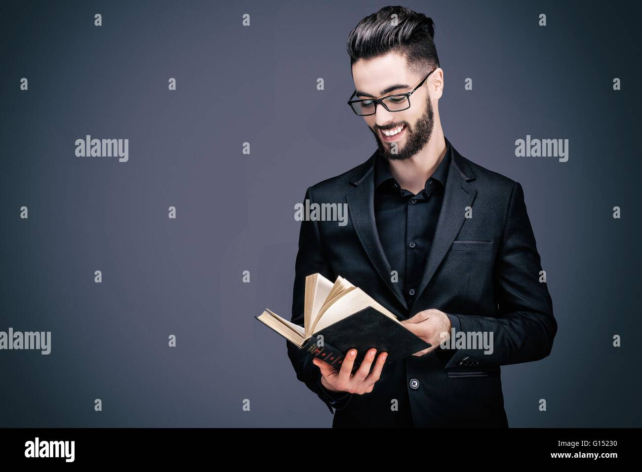 Portrait of a smiling young man in a suit reading a book Stock Photo ...