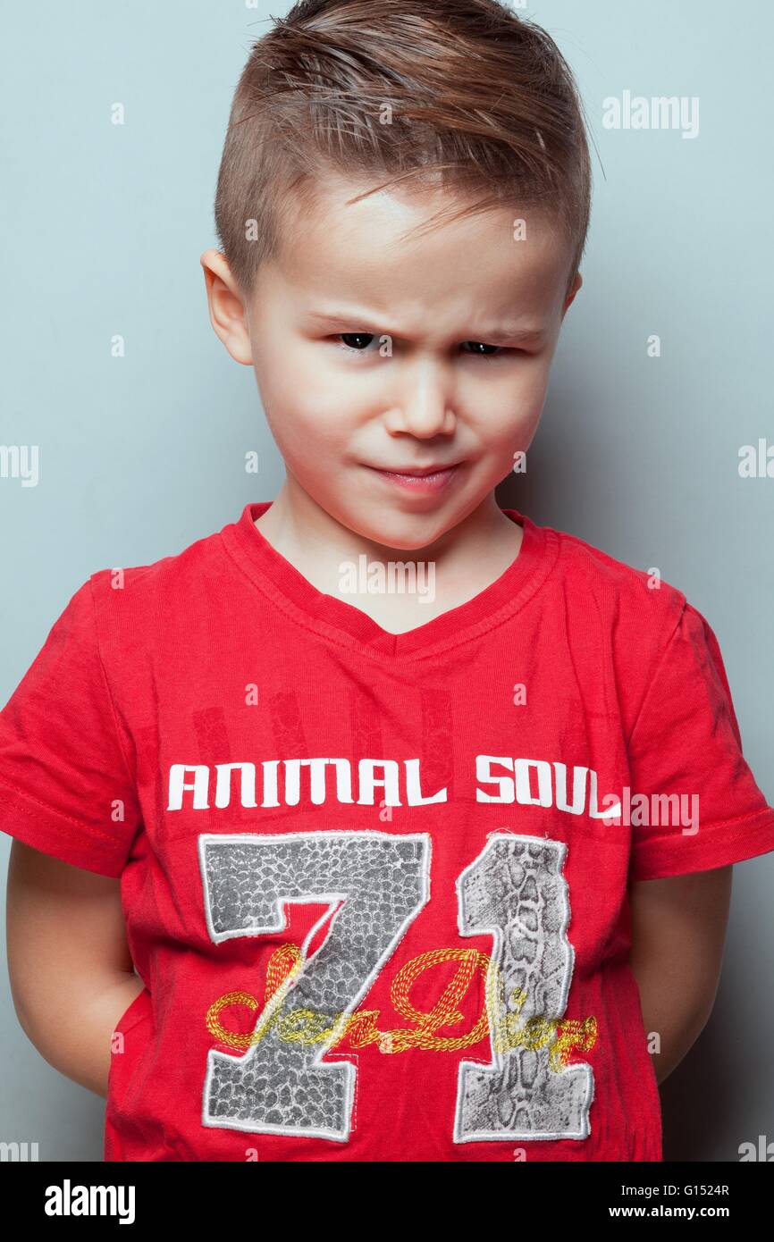 Portrait of an angry boy, arms behind his back, looking toward the lens ...