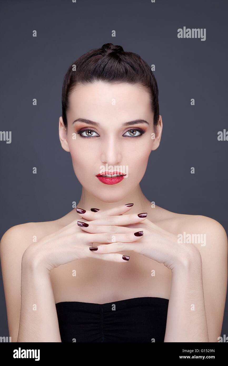 Portrait of a young woman hands under chin, looking toward the lens ...