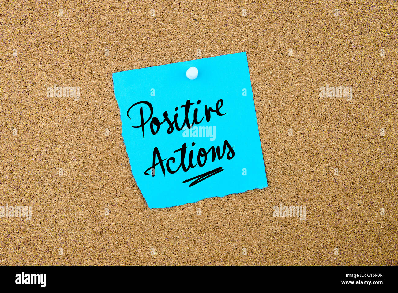 Positive Actions written on blue paper note pinned on cork board with ...