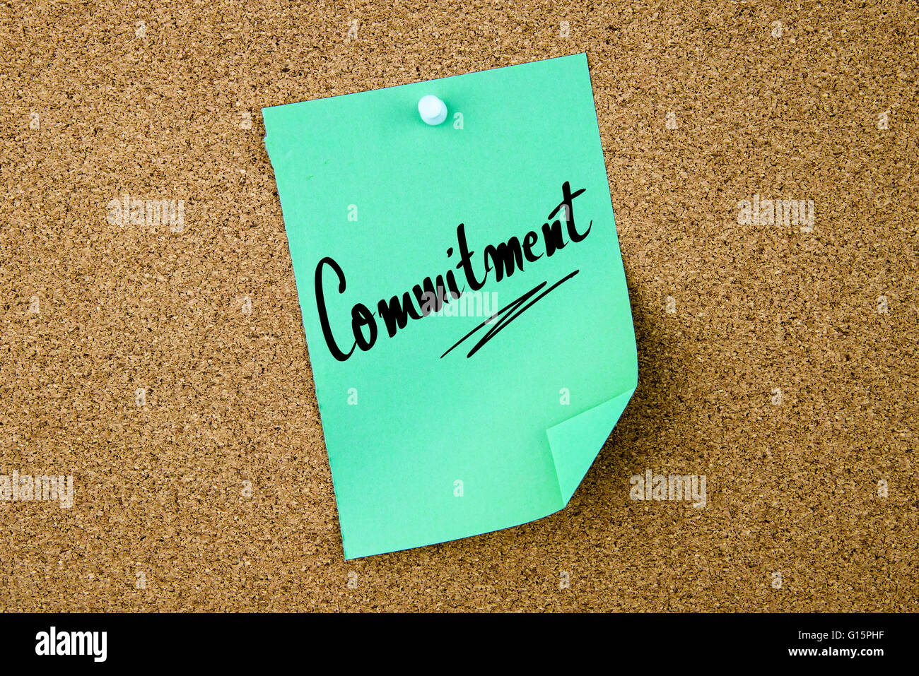 Commitment written on green paper note pinned on cork board with white ...