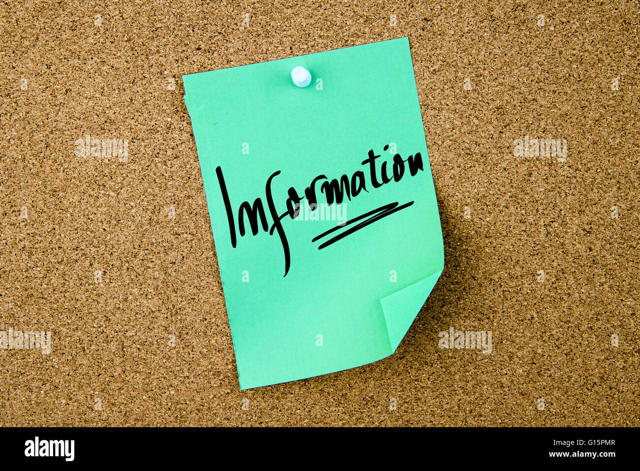 Information written on green paper note pinned on cork board with white ...