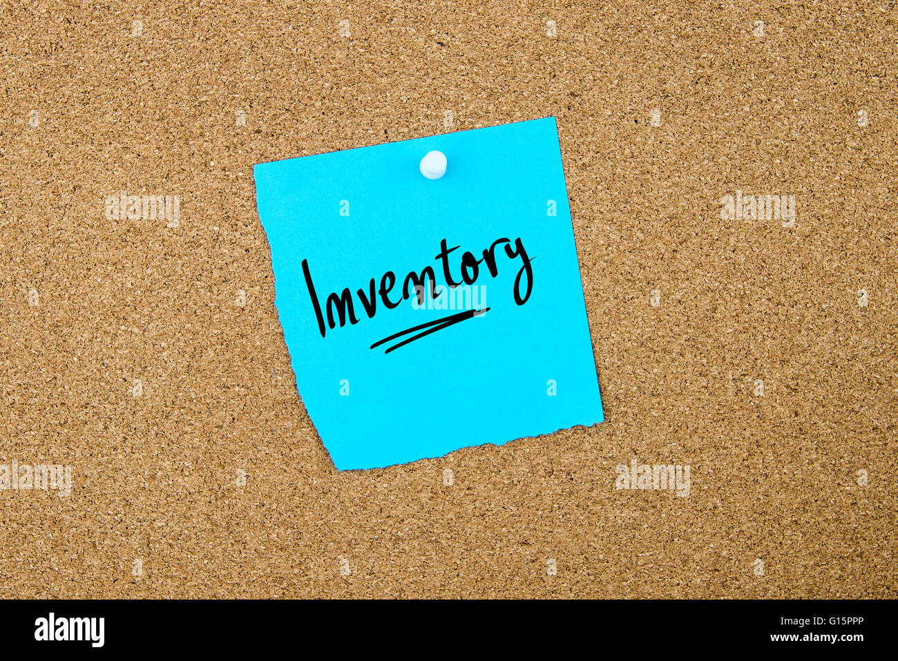 Inventory written on blue paper note pinned on cork board with white ...