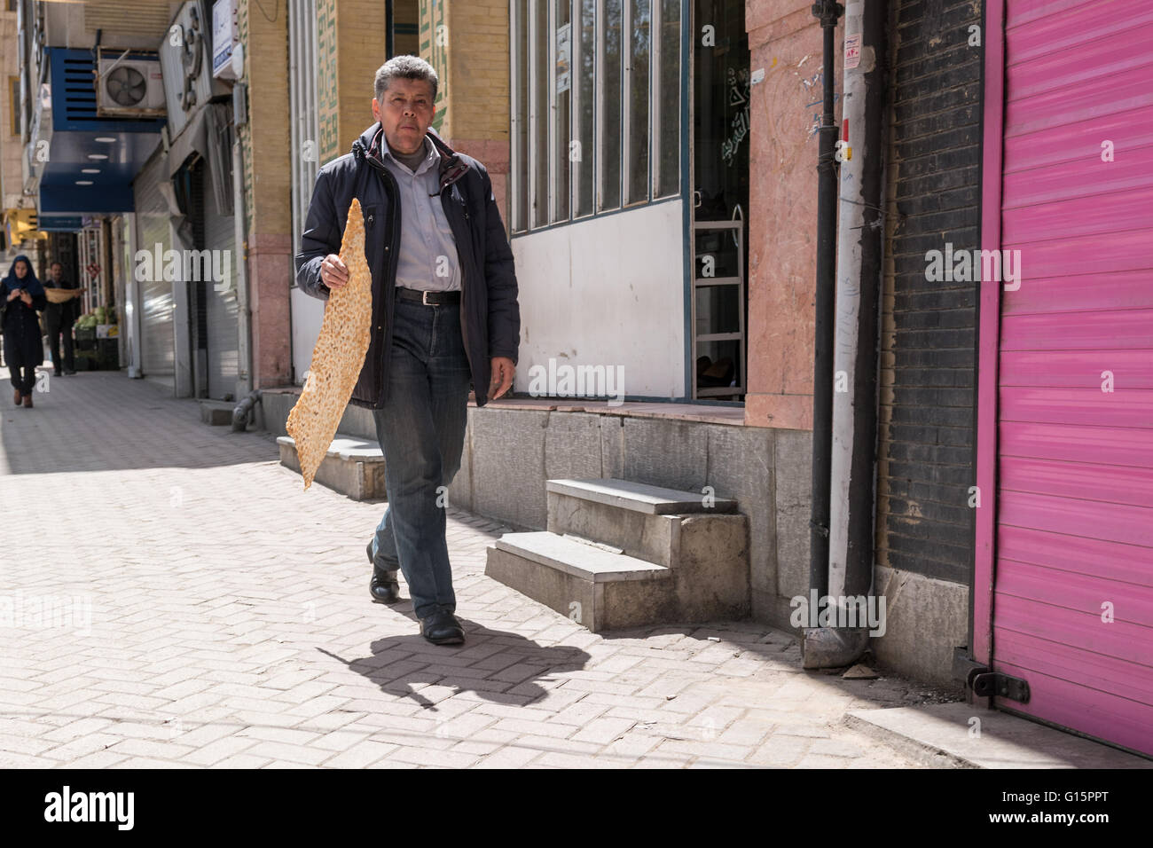 Man carrying fresh piece of sangak bread down the street in Hamadan ...